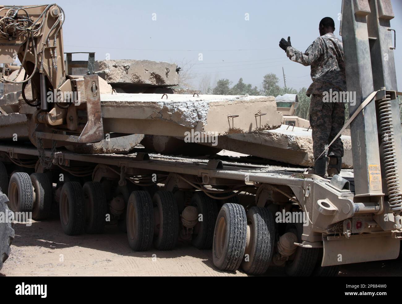 A U.S. Army soldier assists in hauling away concrete barriers as his ...