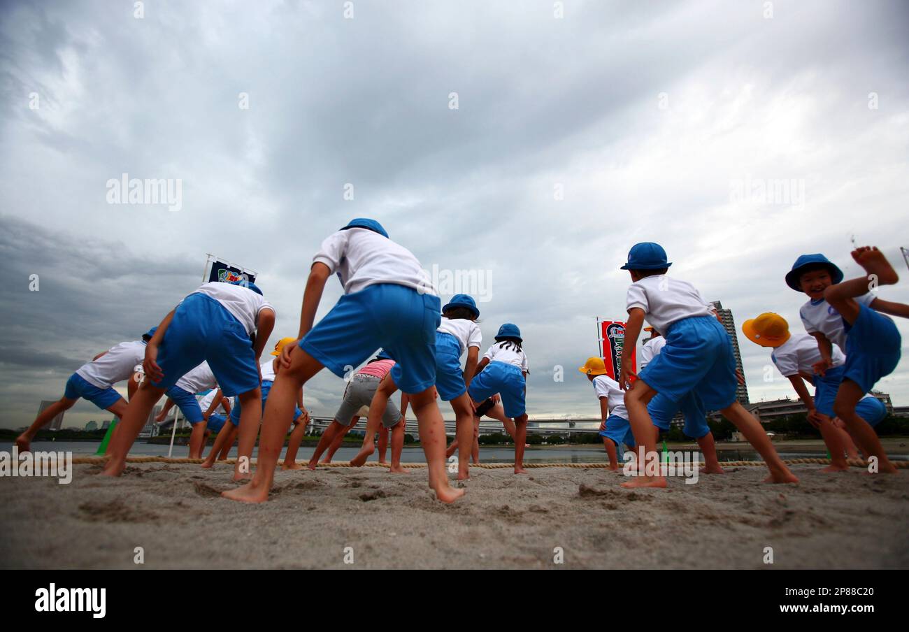 Schoolchildren warm up before a beach sumo promotional event in Tokyo ...