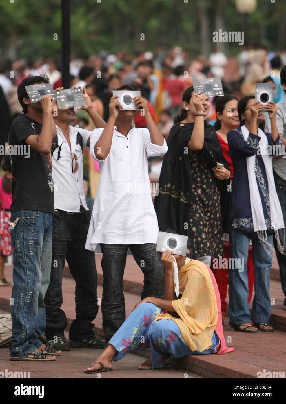 Bangladeshis watch the solar eclipse through specially-designed viewing material in Dhaka ...