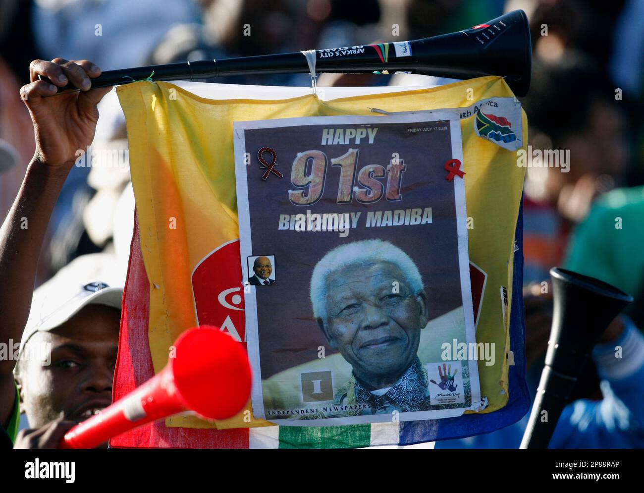 A South African soccer fan holds a poster with Nelson Mandela's face ...