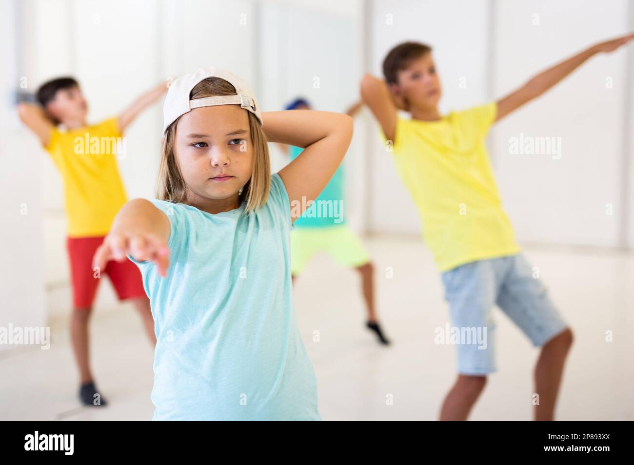 Girl together with other children, learns modern hip hop dance moves in ...
