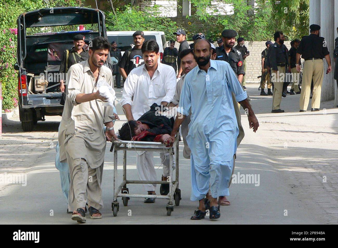 Pakistani paramedics carry a police officer, who was injured in a bomb ...