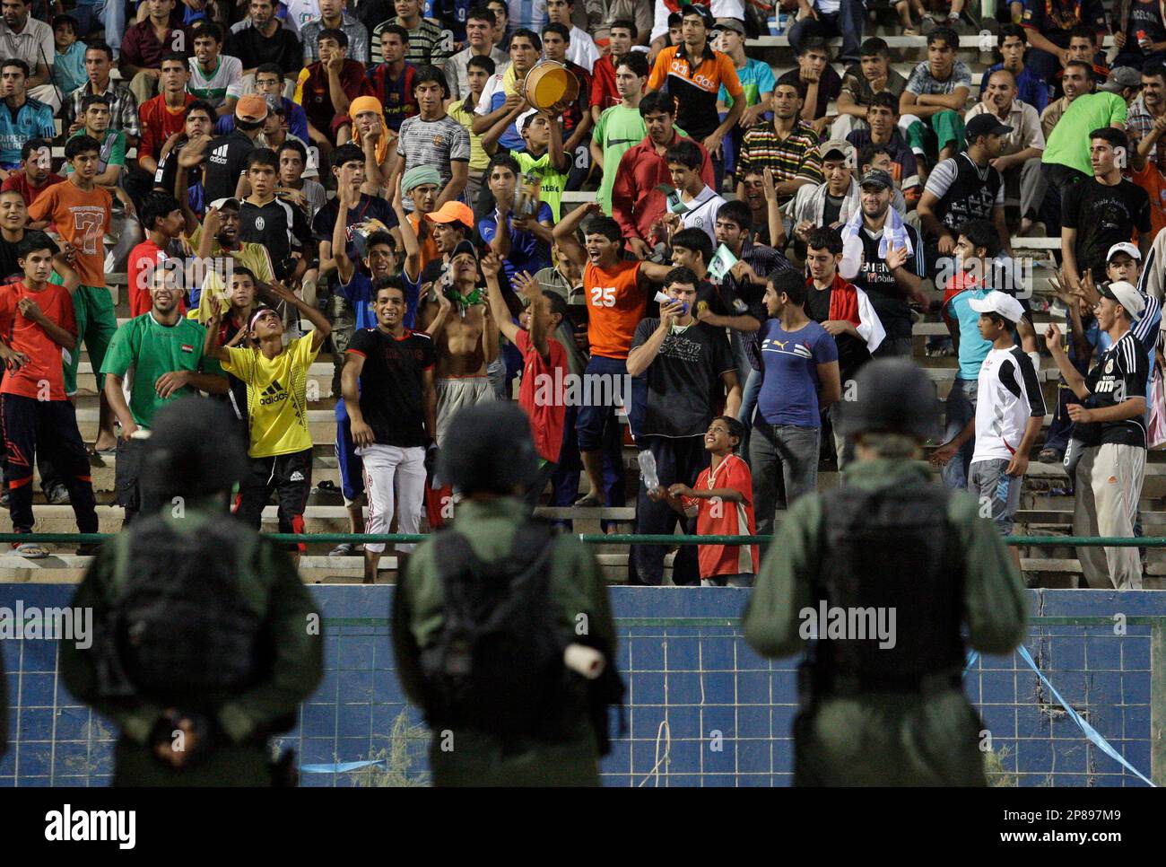 Iraqi Army soldiers stand guard as football fans react during a ...