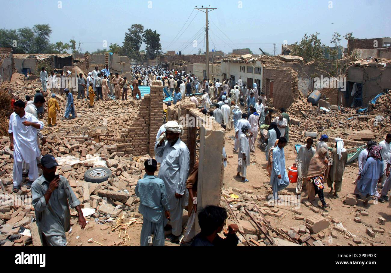 Local residents walk through the rubble at the site of a massive explosion in Mian Channu near ...