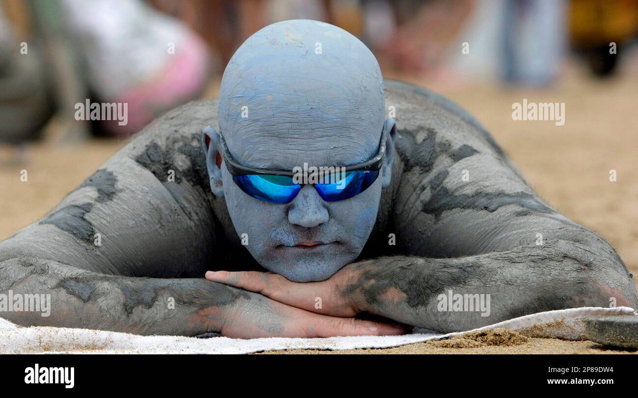 Justin Betteridge from Britain takes a sunbath after mud painting ...