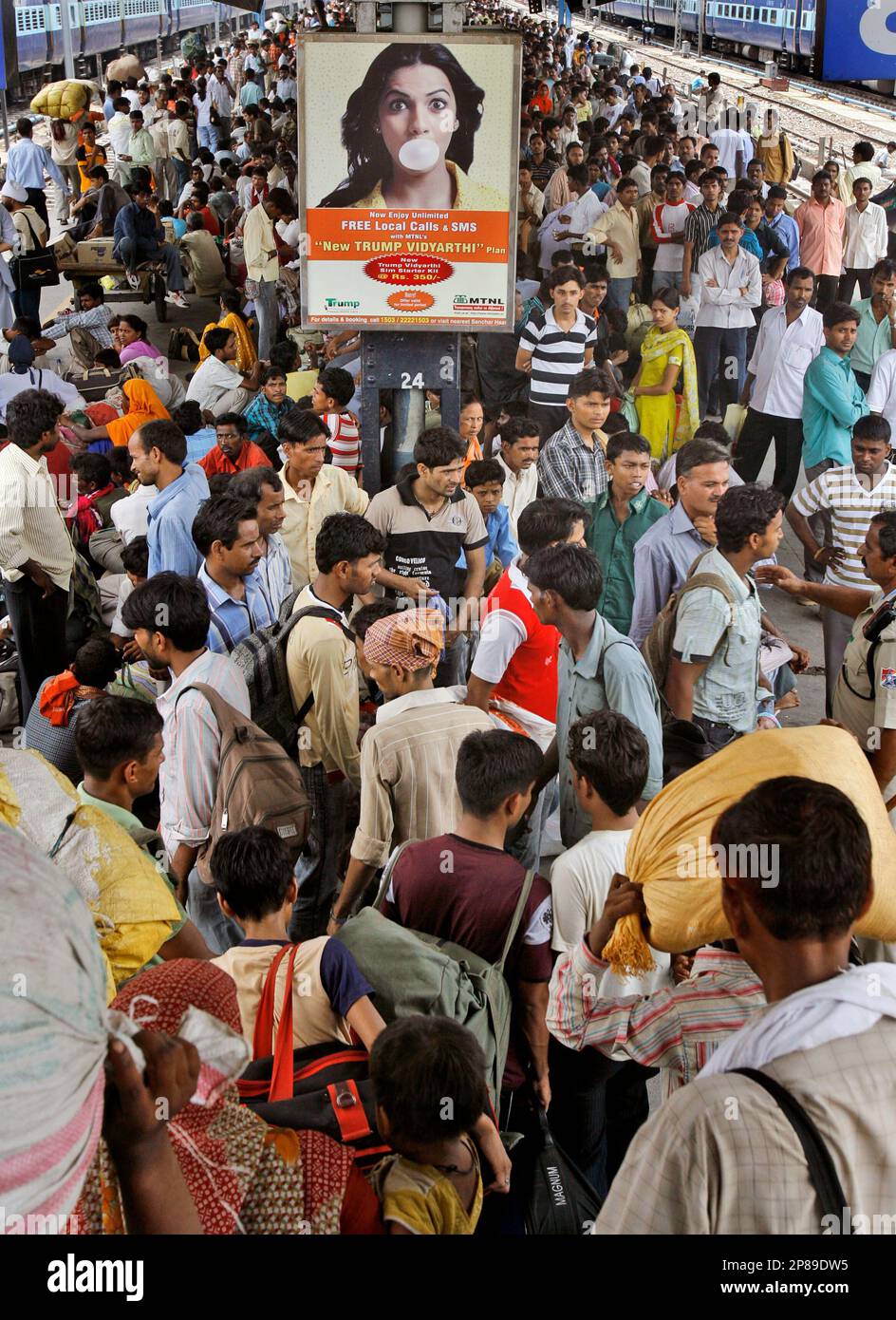 Passengers wait for their trains at an overcrowded railway station, in ...