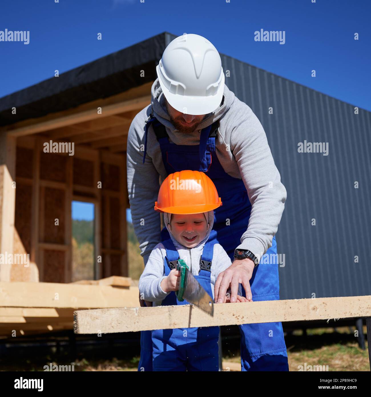 Father with toddler son building wooden frame house. Male builders ...