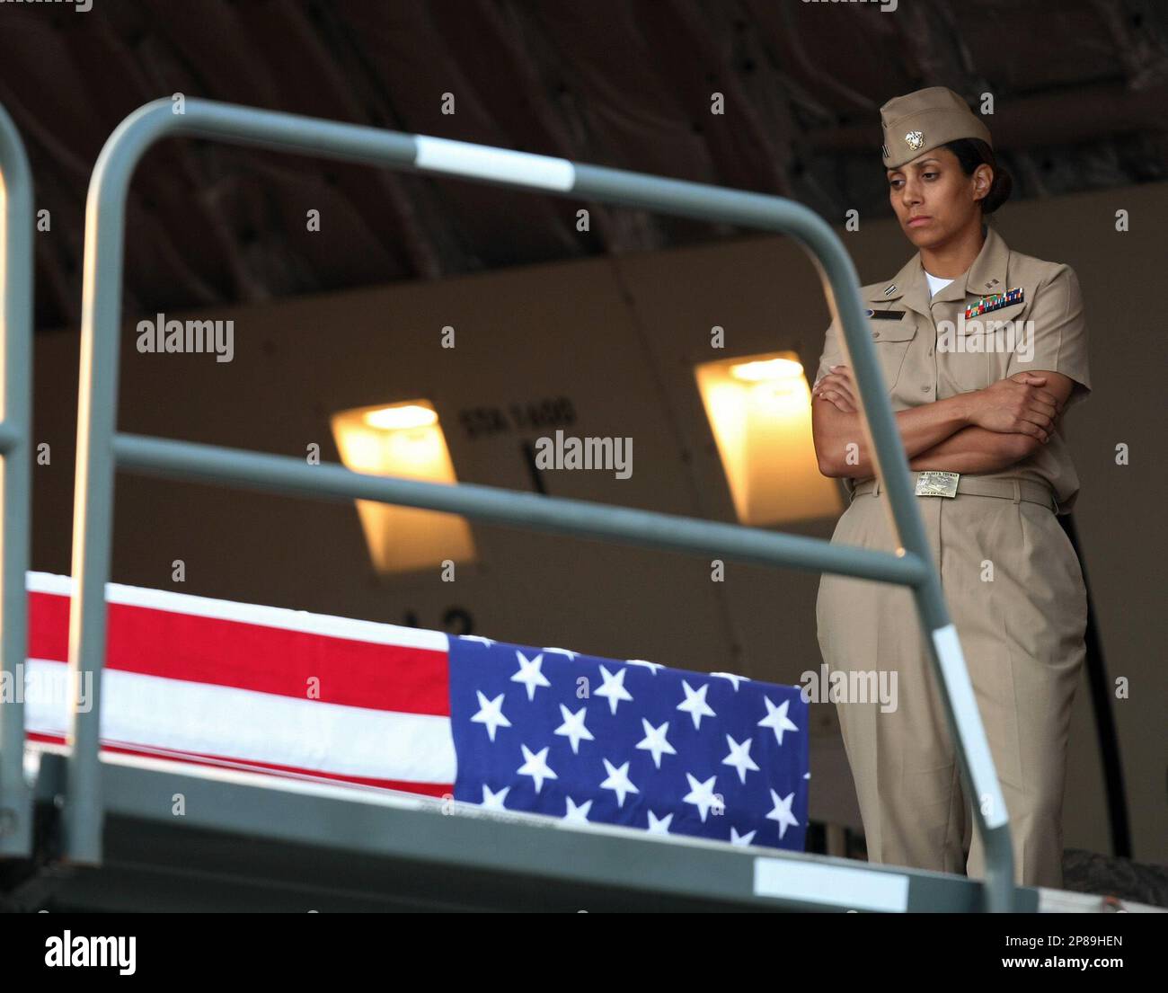 A member of the U.S. Navy waits for a Navy carry team to carry the ...