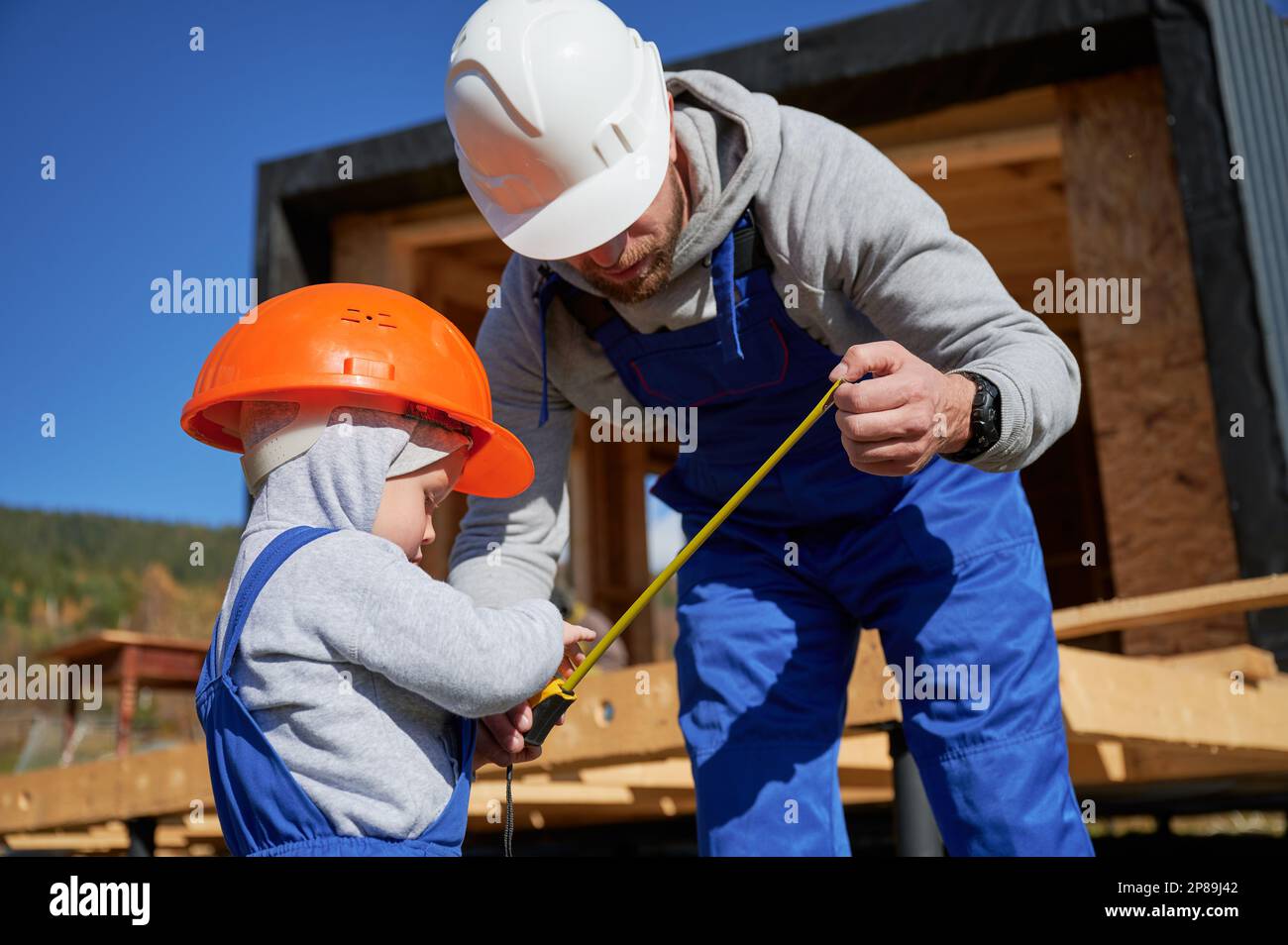 Father with toddler son building wooden frame house. Male builder and ...