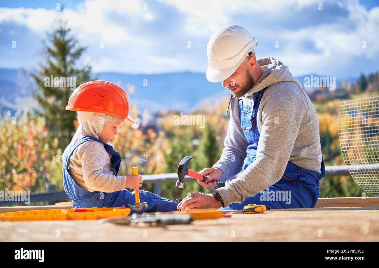 Father with toddler son building wooden frame house. Male builders ...