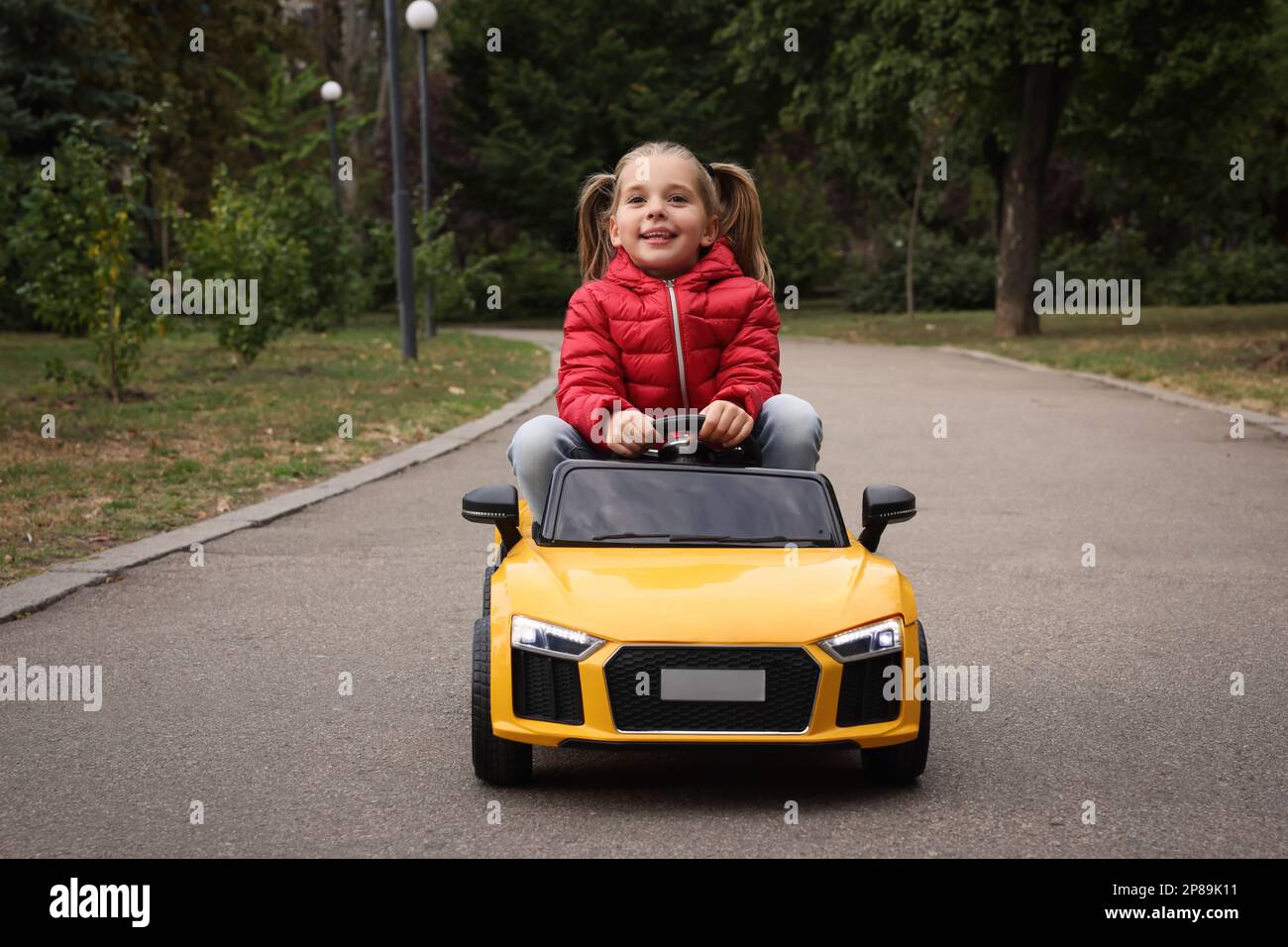 Cute little girl driving children's car outdoors Stock Photo - Alamy