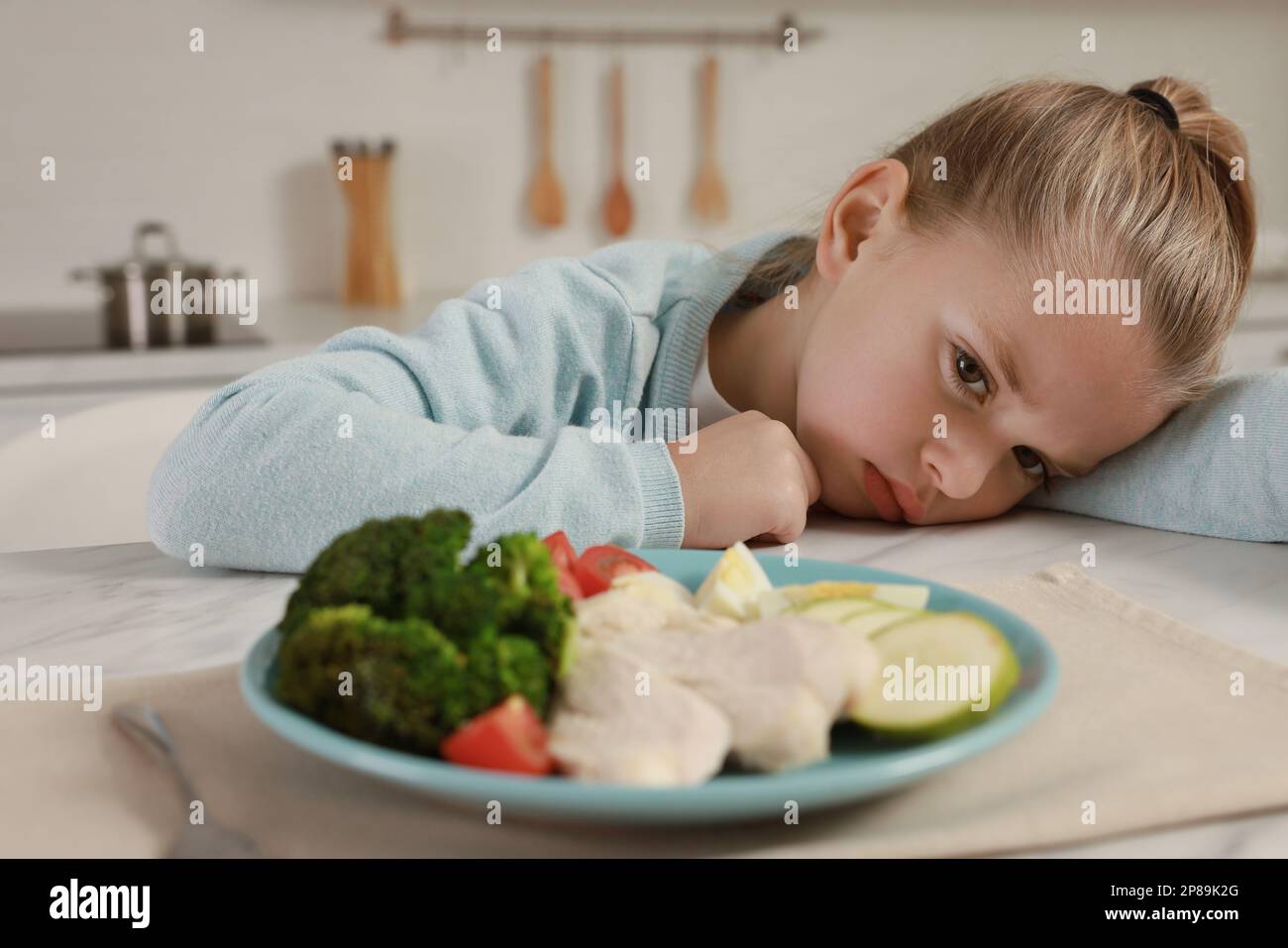 Cute little girl refusing to eat dinner in kitchen Stock Photo - Alamy