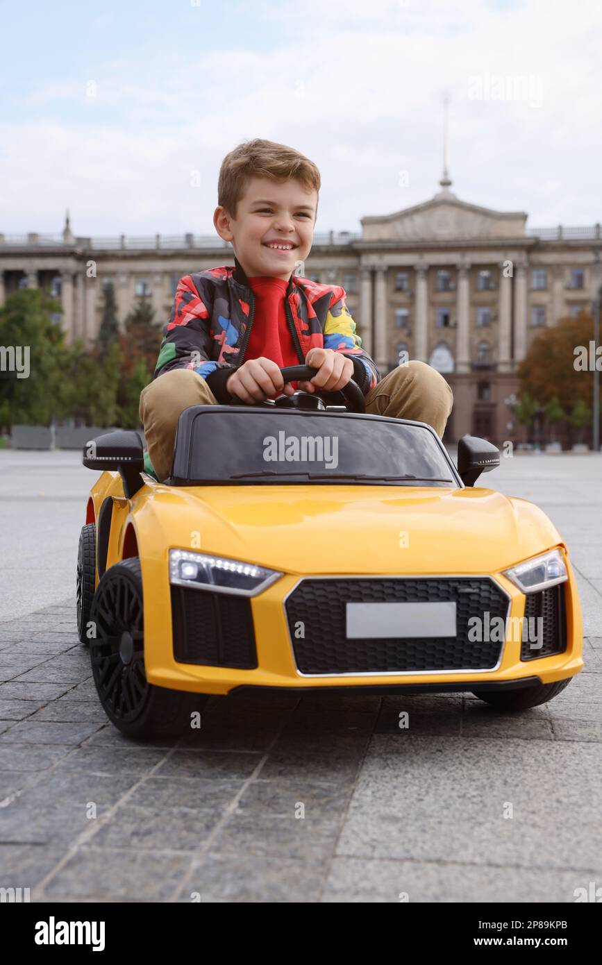 Cute little boy driving children's car on city street Stock Photo - Alamy