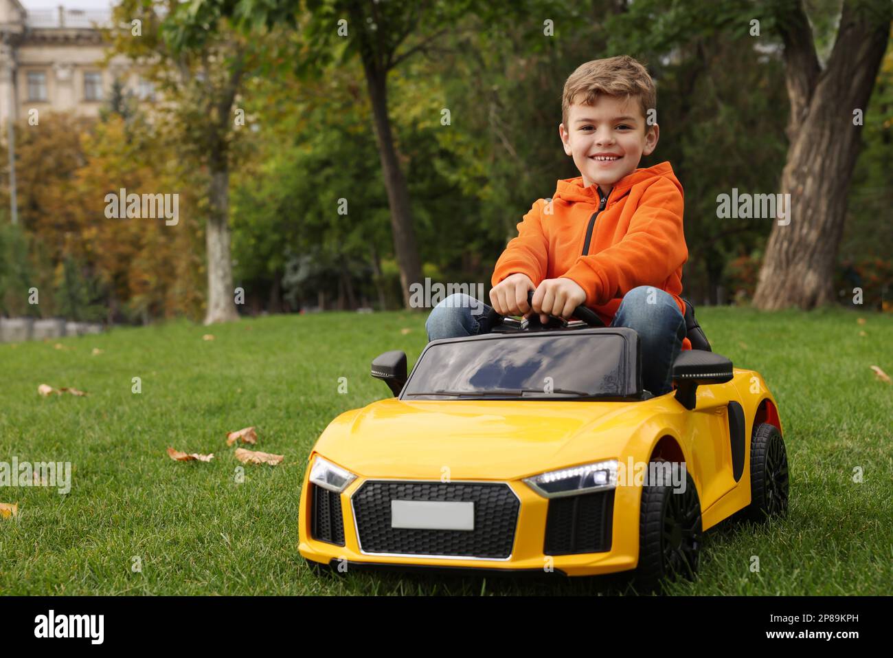 Cute little boy driving children's car in park. Space for text Stock ...