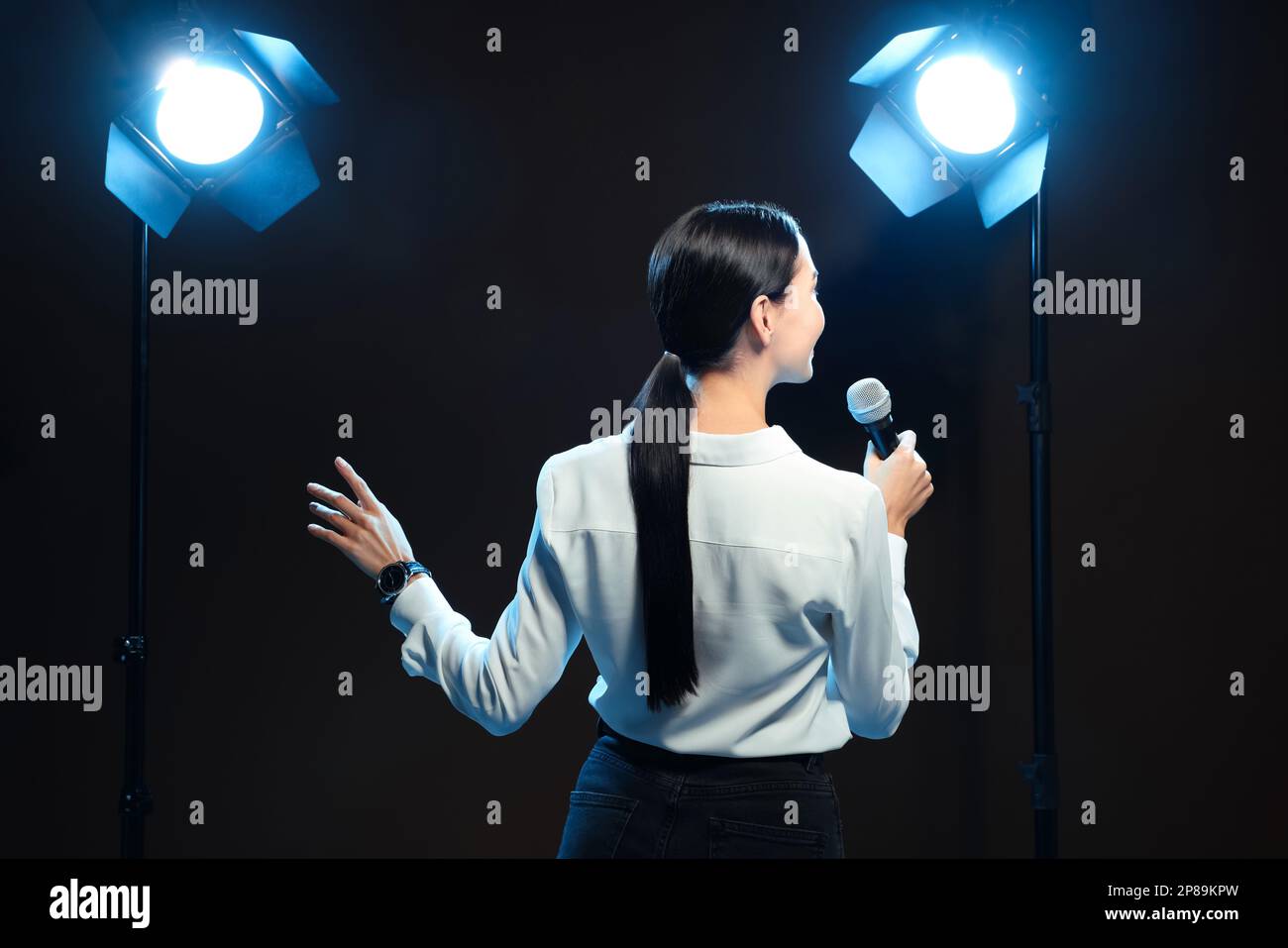Motivational speaker with microphone performing on stage, back view ...