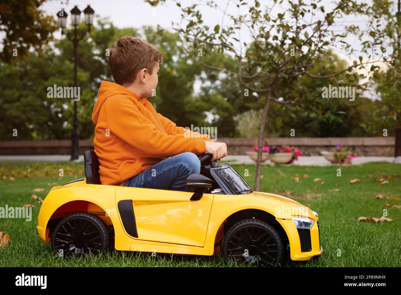 Cute little boy driving children's car in park Stock Photo - Alamy