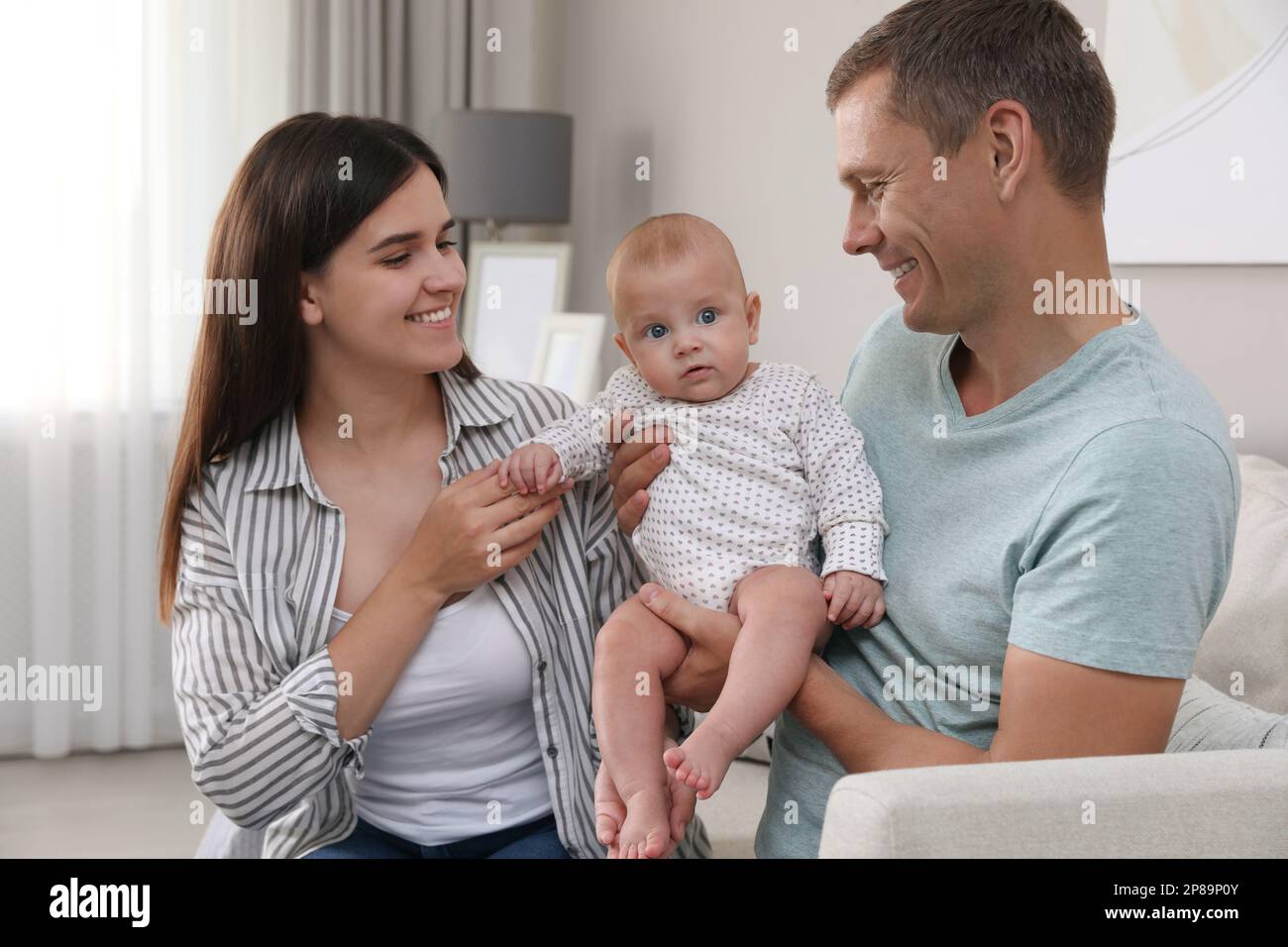 Happy family with their cute baby in living room at home Stock Photo ...