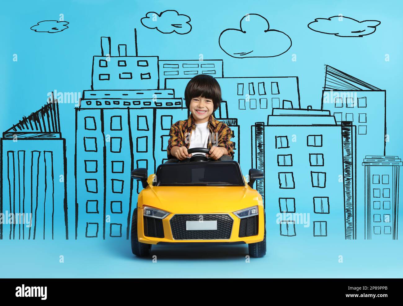 Cute little boy driving toy car and drawing of city on light blue ...