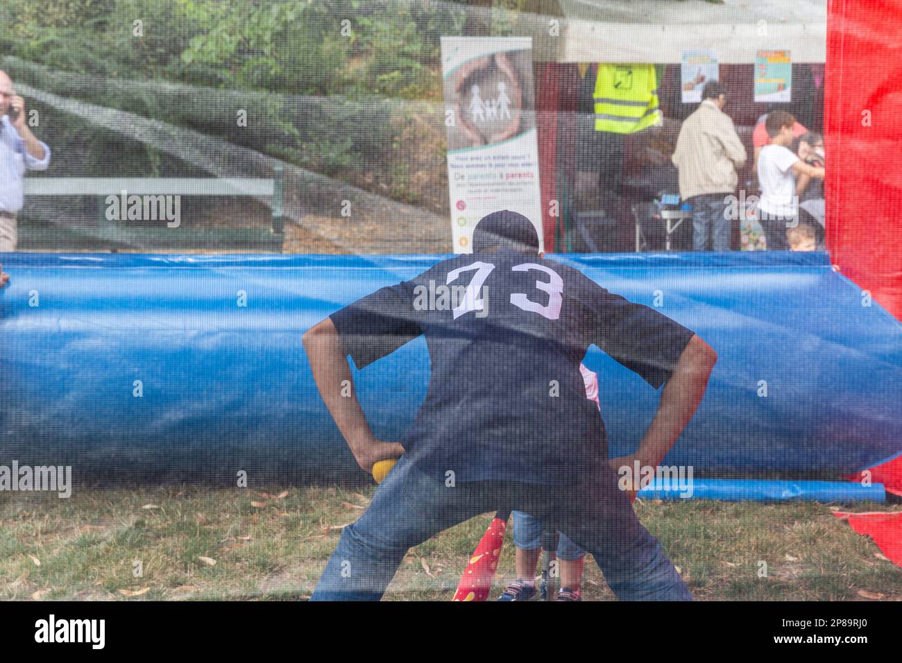 Coach, seen from behind, teaching the basics of baseball to a young ...