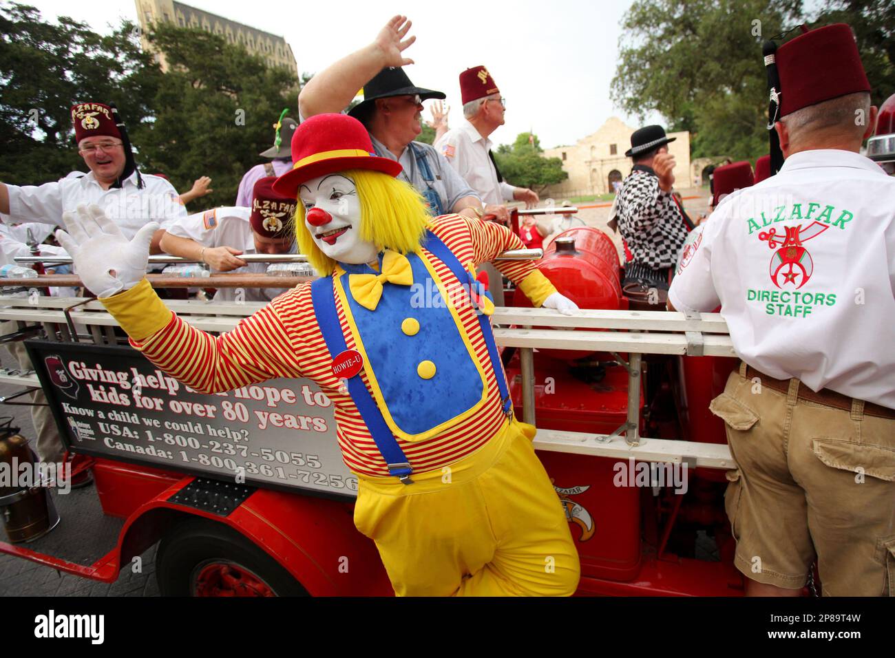 "Howie-U" the clown, middle, and fellow Shriners wave to spectators ...