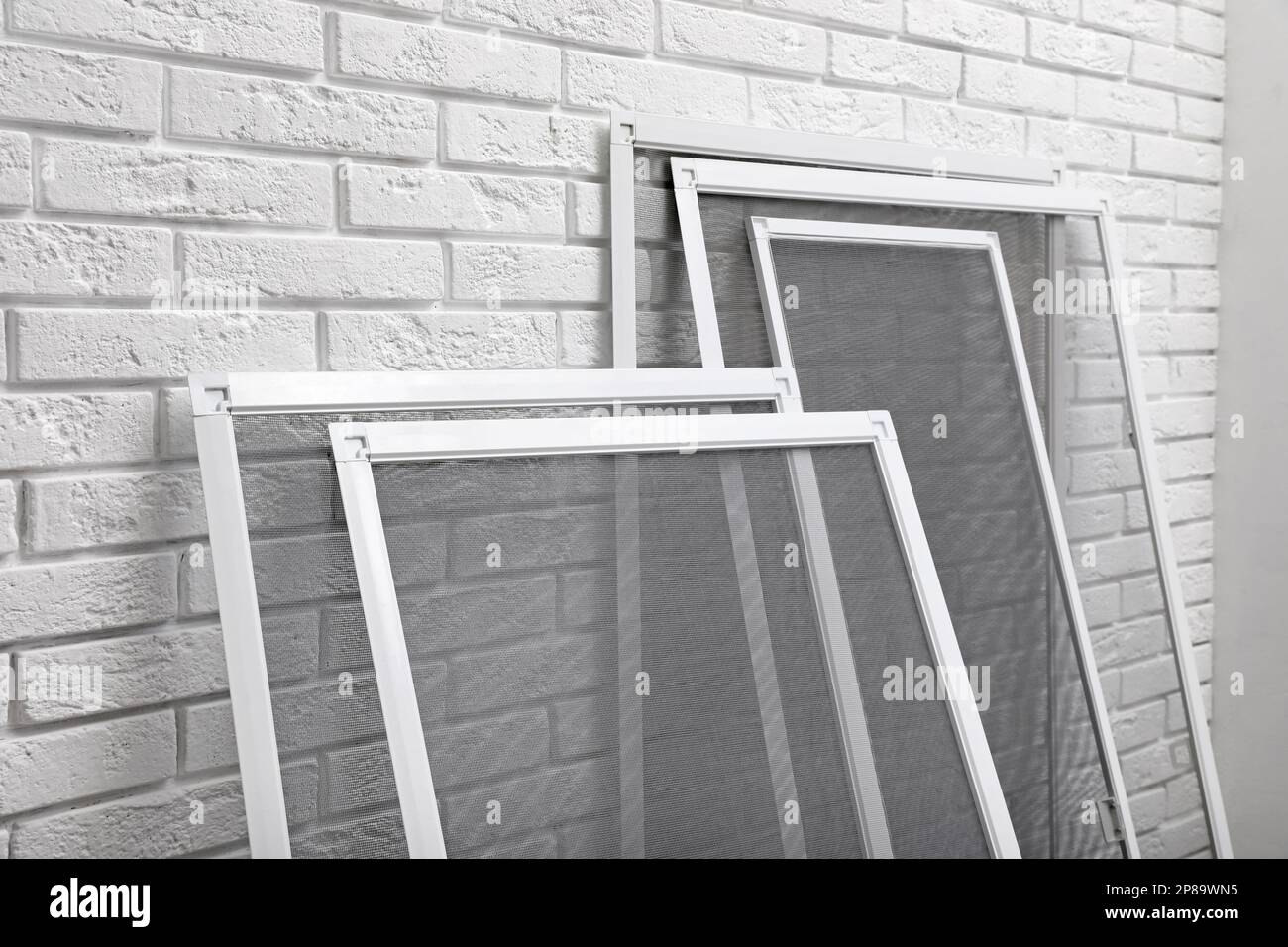 Set of window screens near white brick wall Stock Photo - Alamy