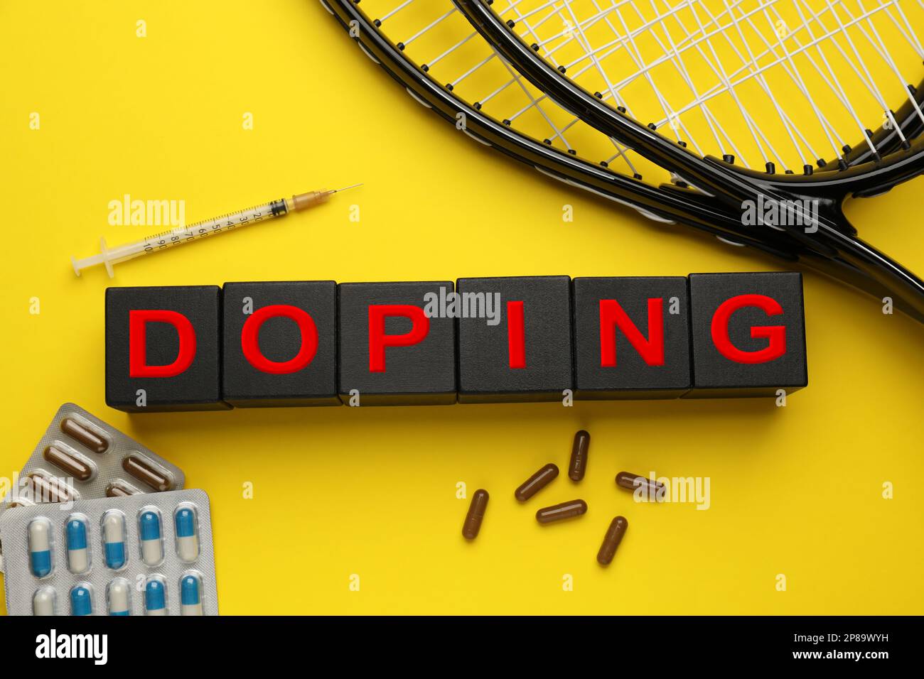 Black wooden cubes with word Doping, tennis rackets and drugs on yellow ...