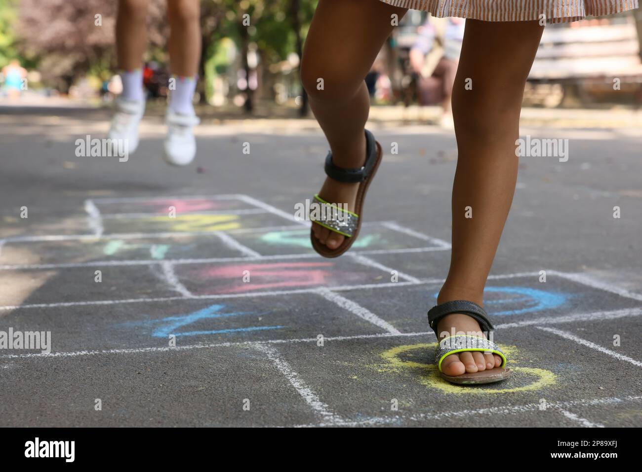 Little children playing hopscotch drawn with chalk on asphalt outdoors ...