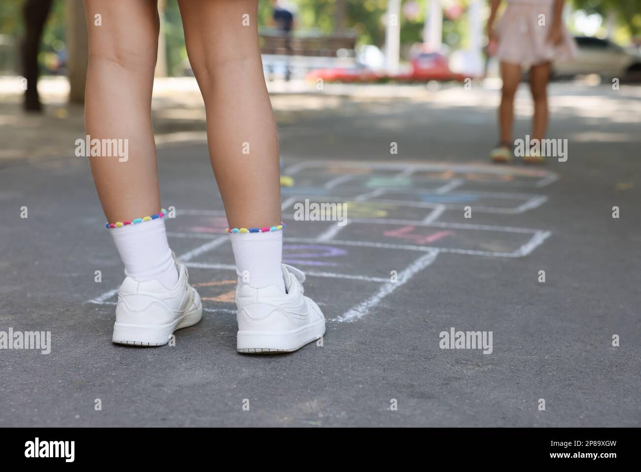Little children playing hopscotch drawn with chalk on asphalt outdoors ...