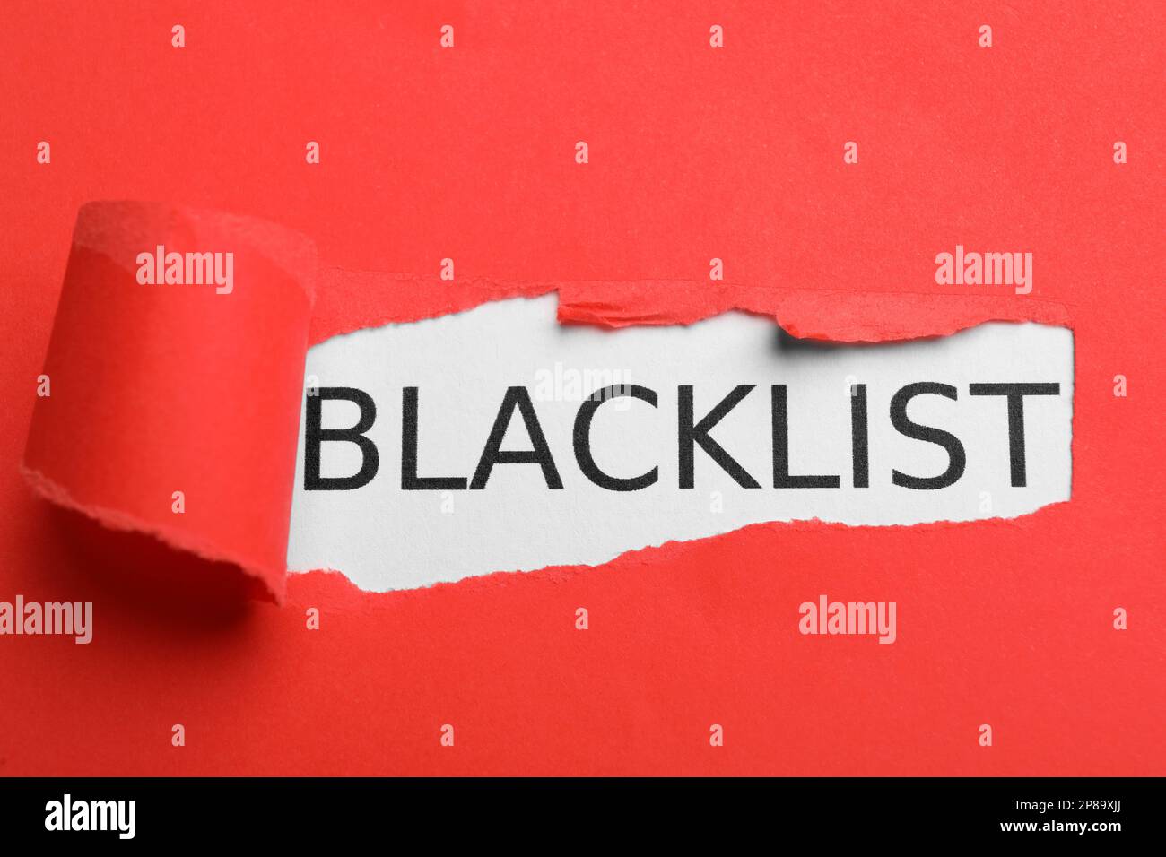 Word Blacklist on white background through hole in red paper, top view ...