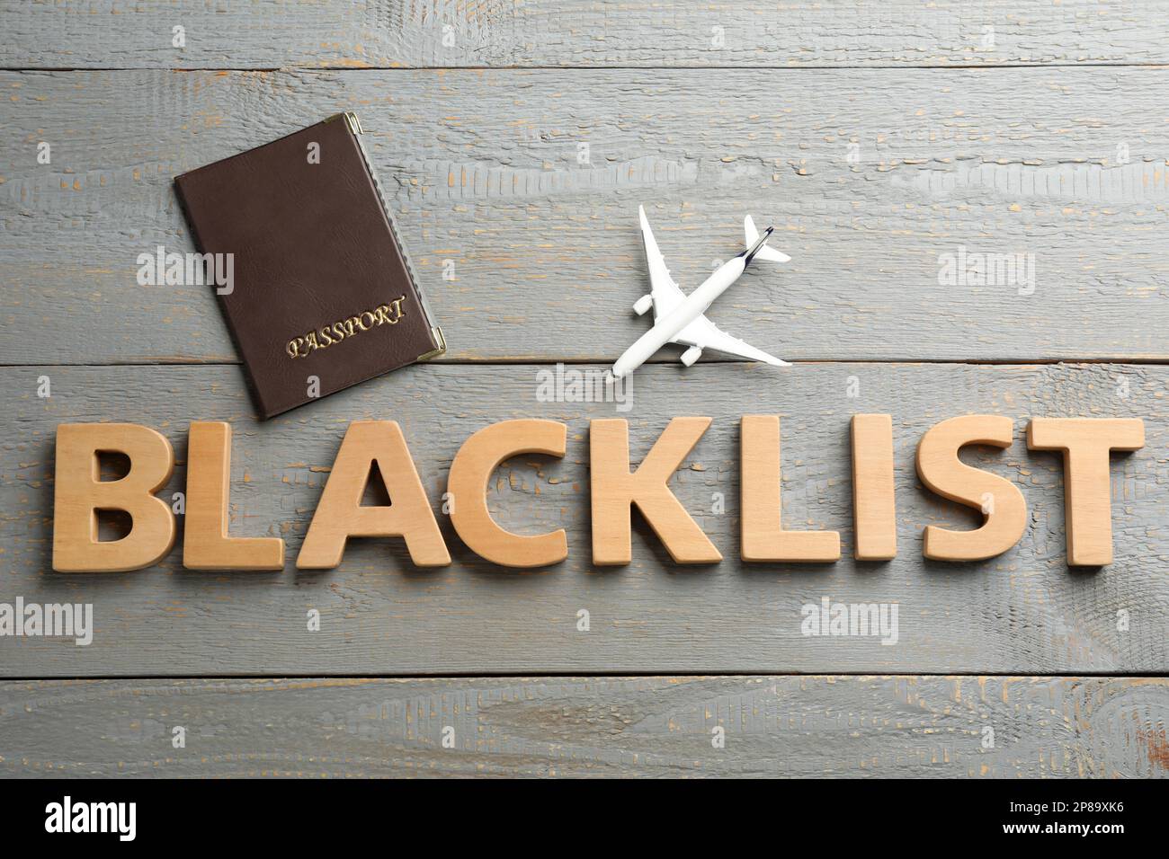 Word Blacklist of letters, toy airplane and passport on grey wooden ...