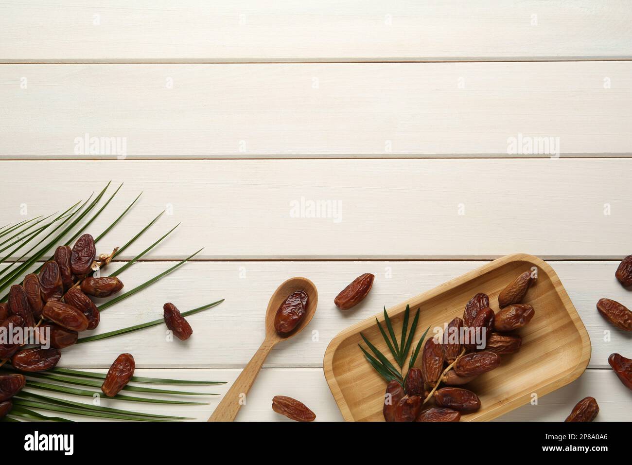 Flat lay composition with tasty sweet dried dates on white wooden table ...