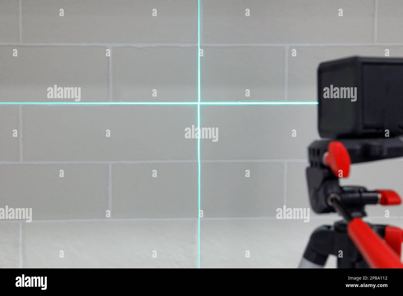 Cross lines of laser level on white brick wall Stock Photo - Alamy