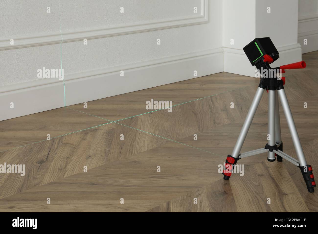 Cross line laser level with tripod on wooden floor indoors Stock Photo ...