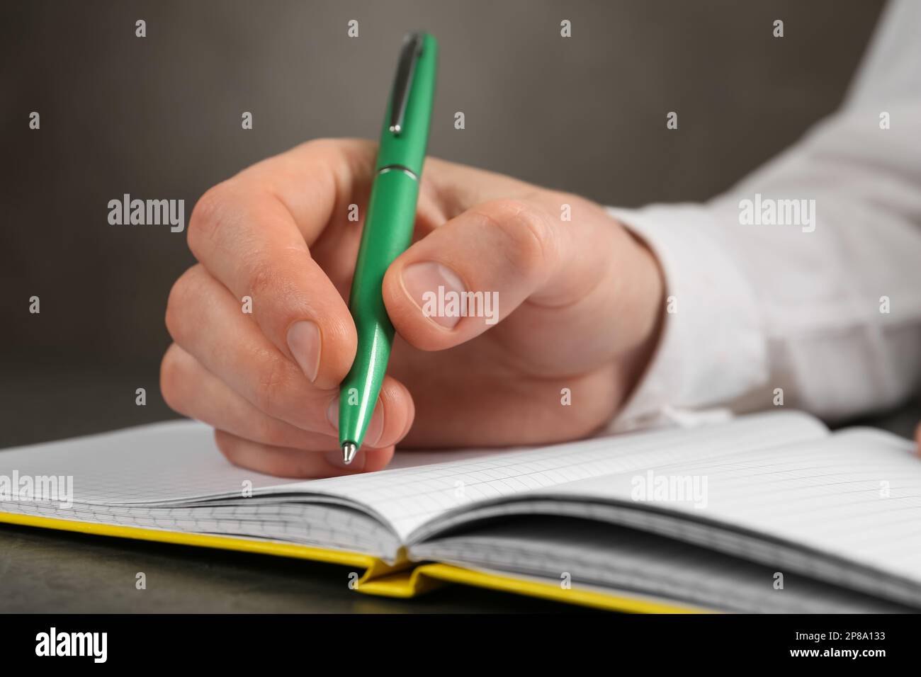 Man writing with pen in notebook at grey table, closeup of hand Stock ...