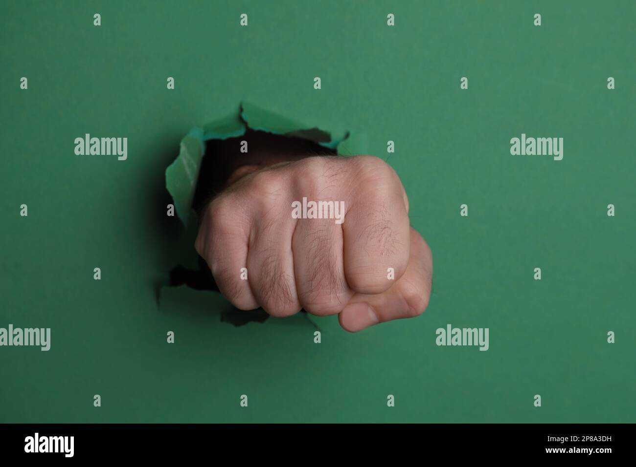 Man breaking through green paper with fist, closeup Stock Photo - Alamy