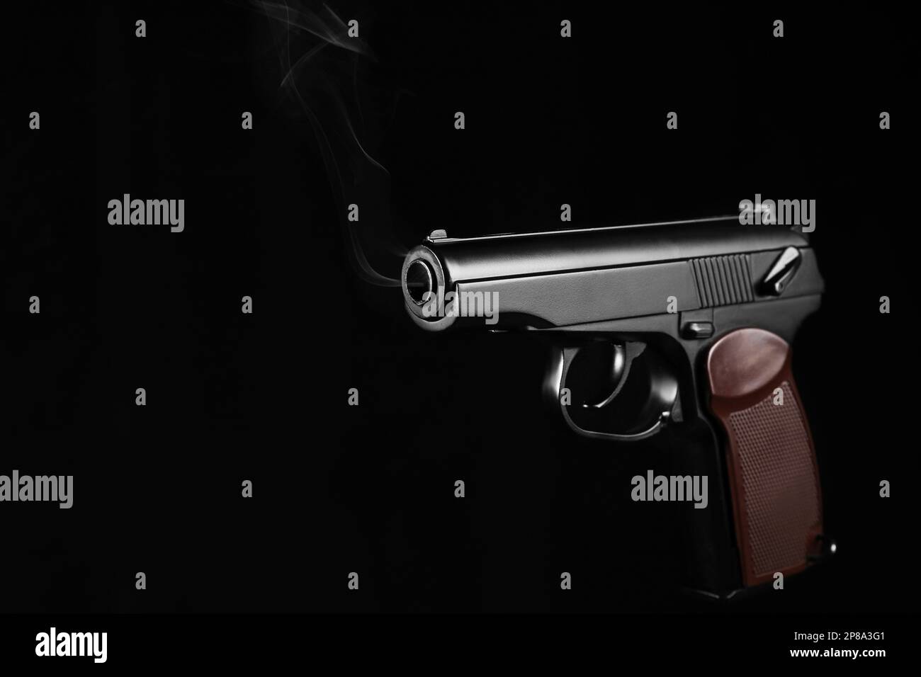 Handgun with smoke coming out of barrel on dark background, space for ...