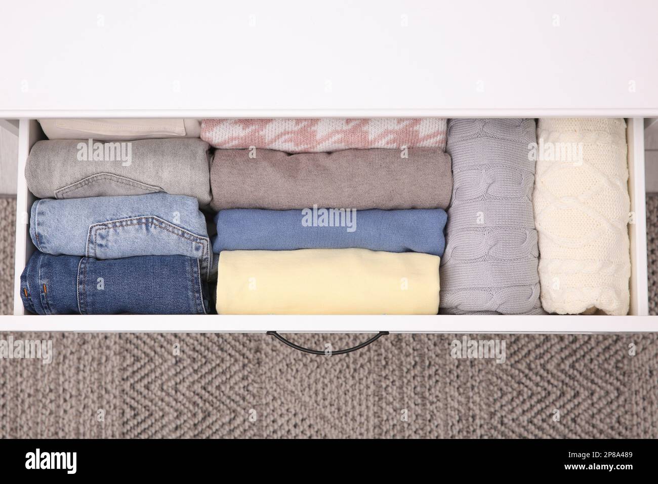 Open drawer with folded clothes indoors, top view. Vertical storage ...