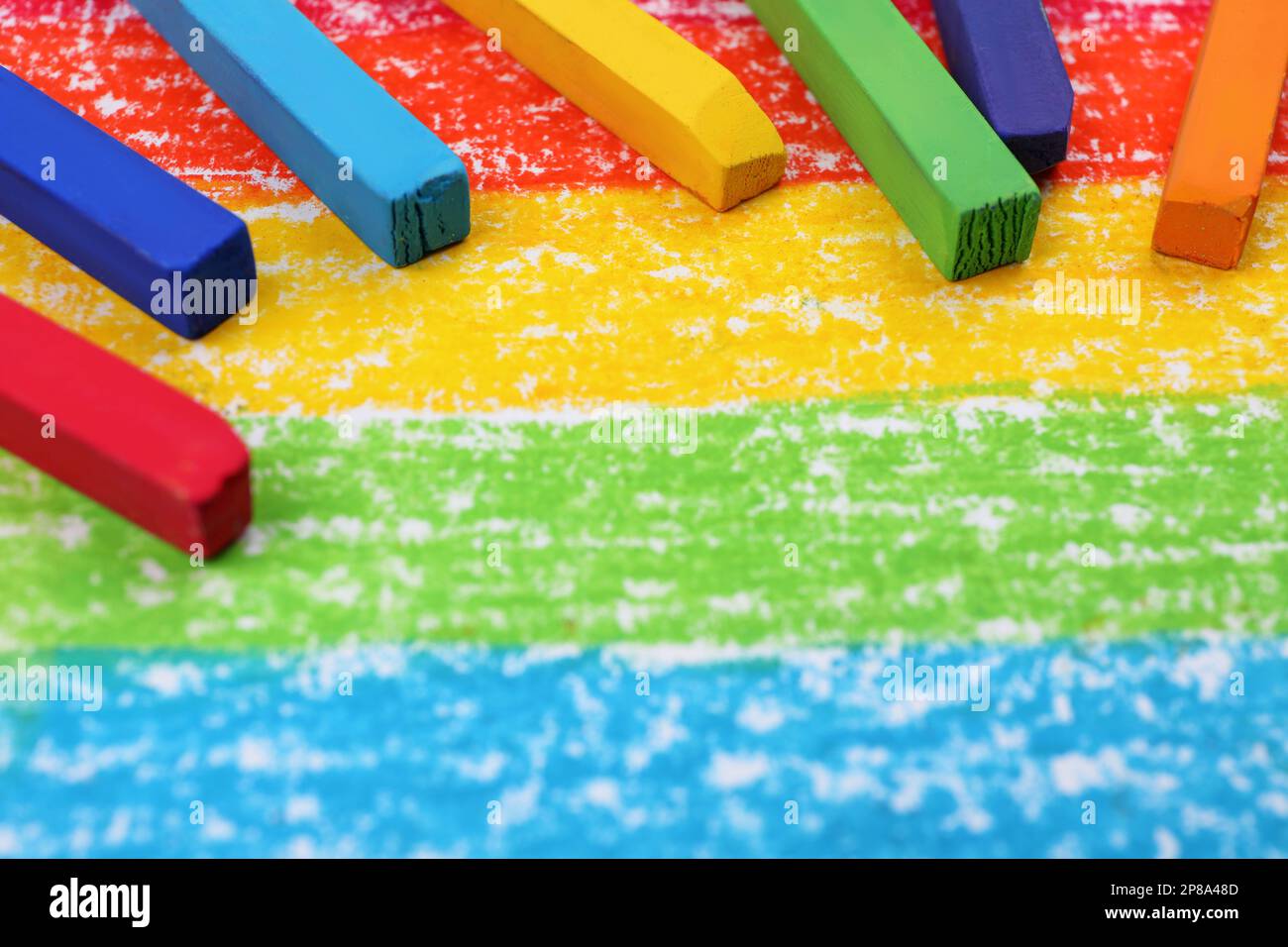 Colorful pastel chalks on drawing of rainbow, closeup. Space for text ...
