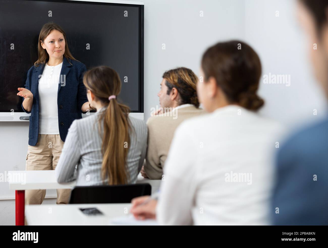 Competent female tutor teaching students in college classroom Stock ...