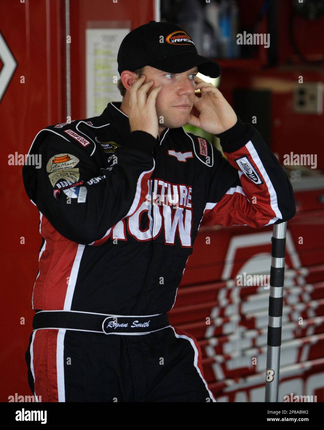 Regan Smith covers his ears as his crew works on the engine of his car ...