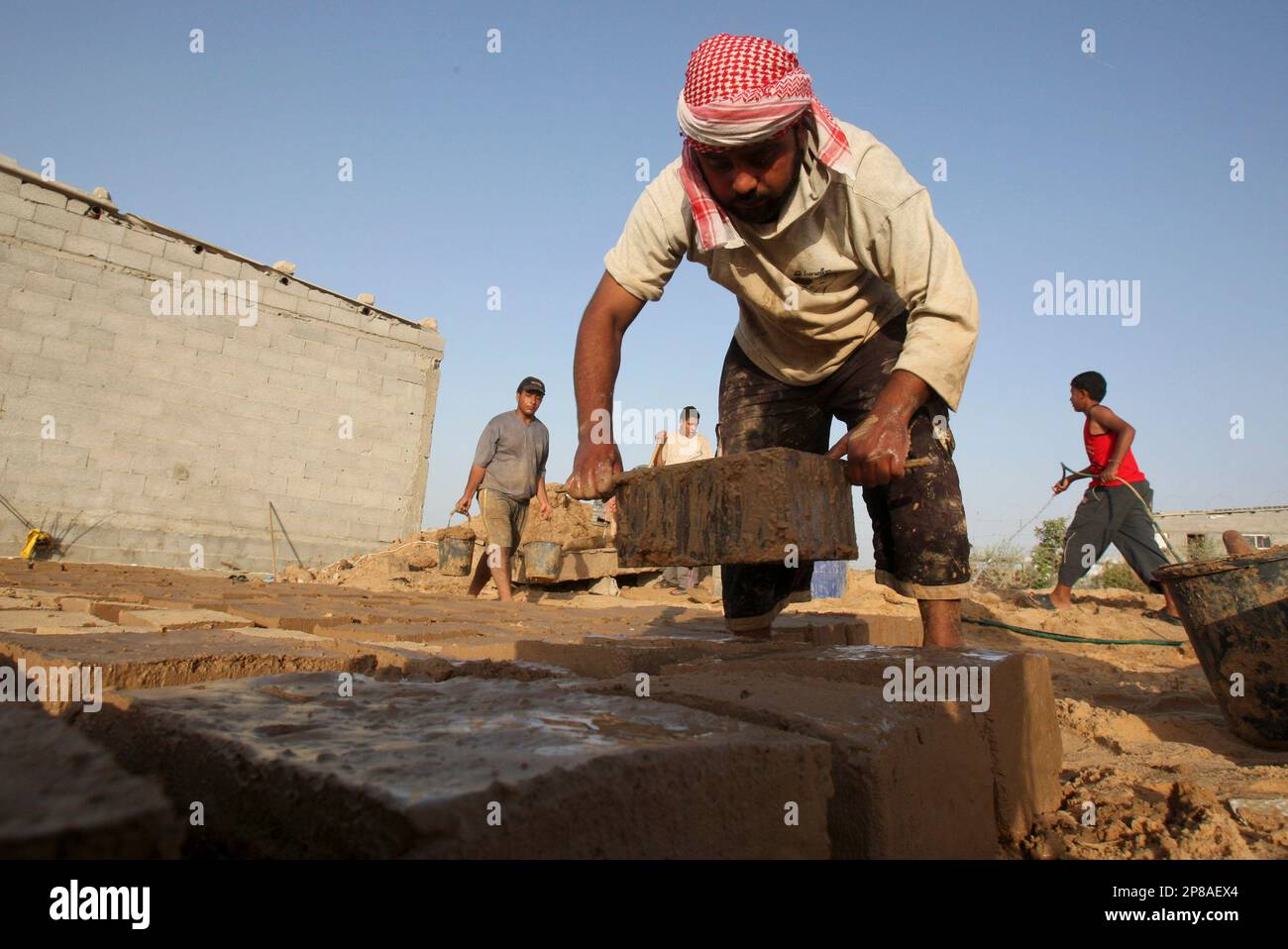 A Palestinian worker prepares blocks of clay for the construction of ...