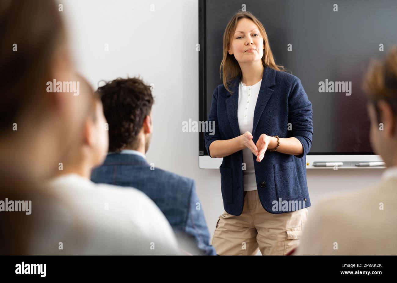 Knowledgeable female professor explaining subject to classroom full of ...