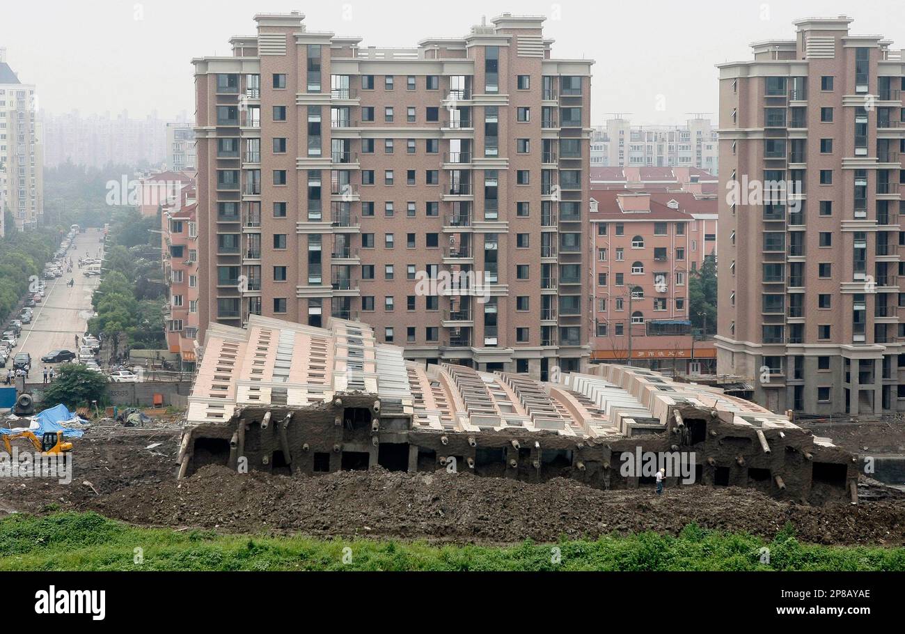 Chinese men are seen near the collapsed 13-floor residential building ...