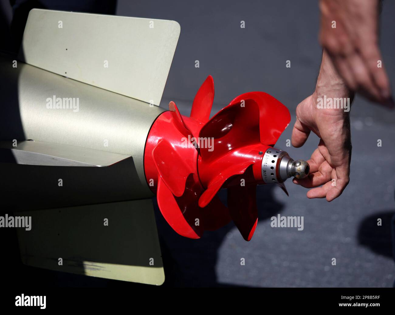 A sailor gently touches the propeller as crew remove a torpedo from its ...