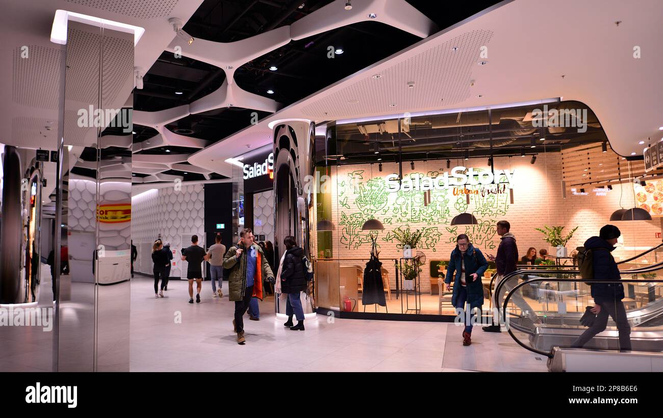 Warsaw, Poland. 8 March 2023. People walking in a shopping mall past the shops. Shopping passage ...