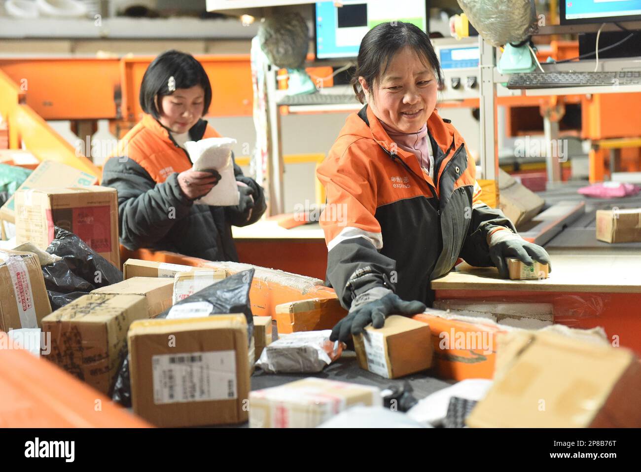 Female workers sort express packages on the assembly line in the e ...