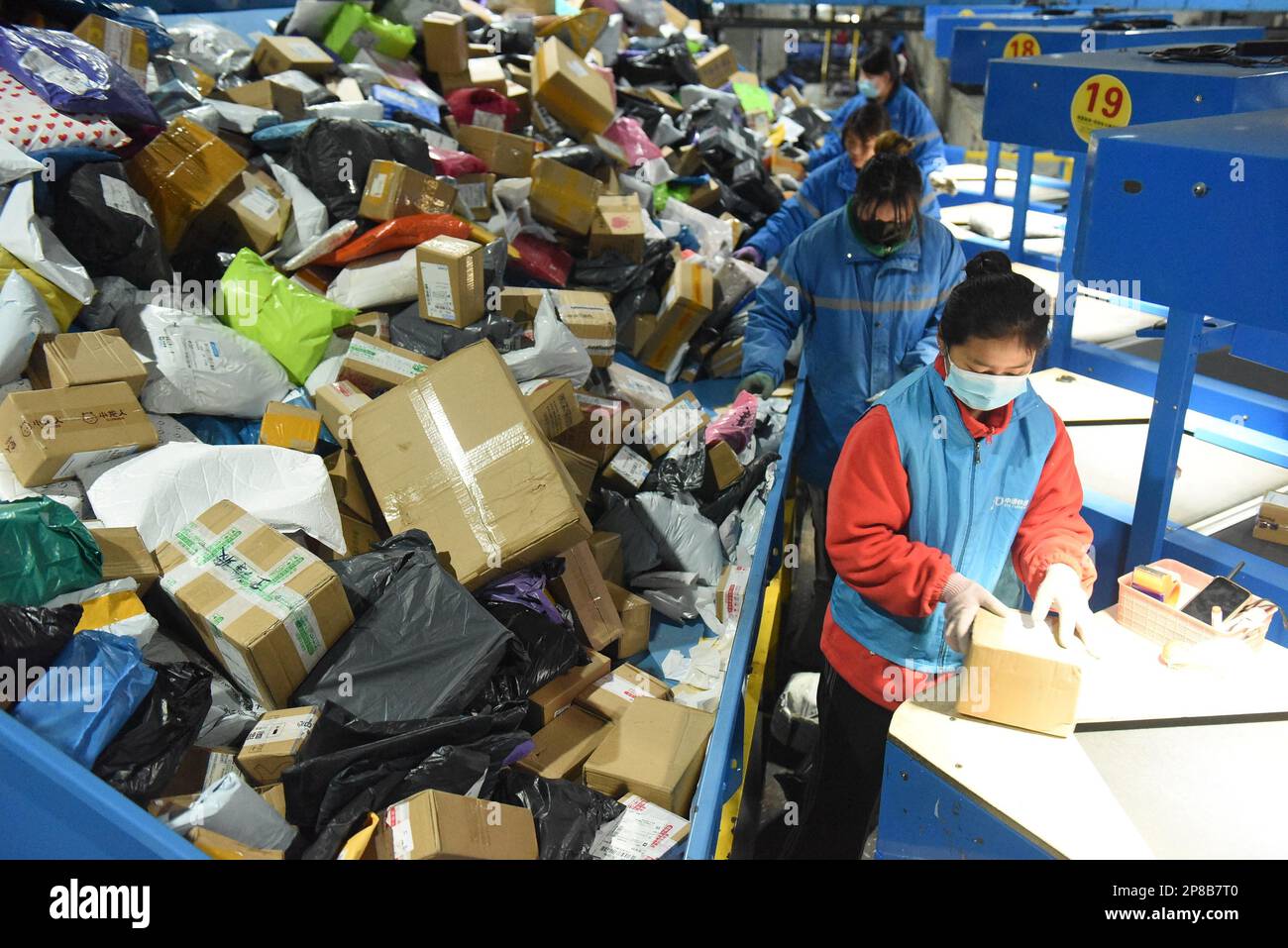 Female workers sort express packages on the assembly line in the e ...