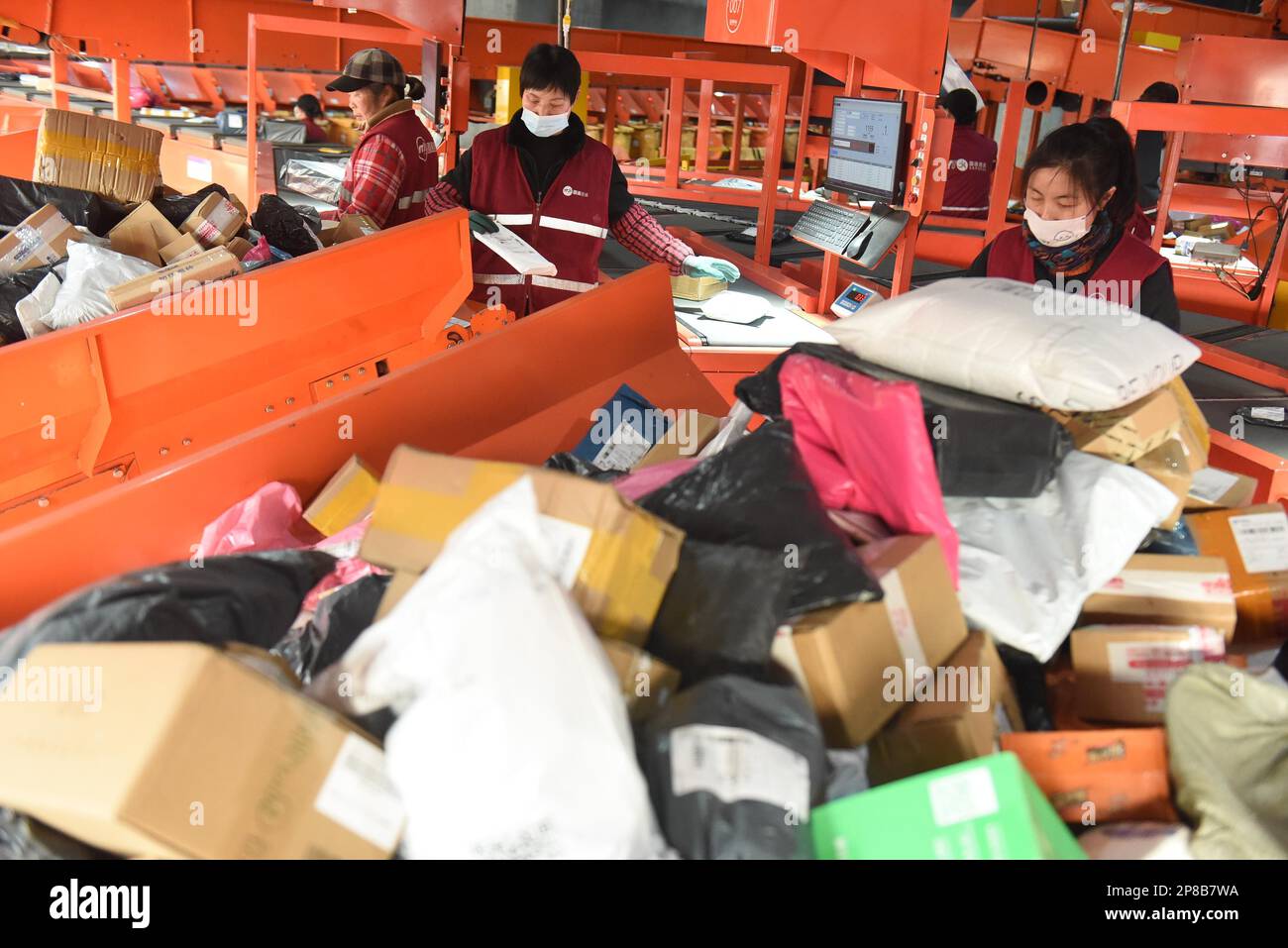 Female workers sort express packages on the assembly line in the e ...