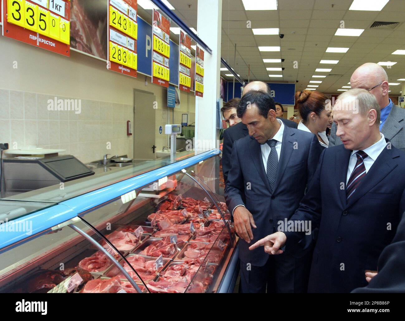 Russian Prime Minister Vladimir Putin, right, looks at meat on display ...