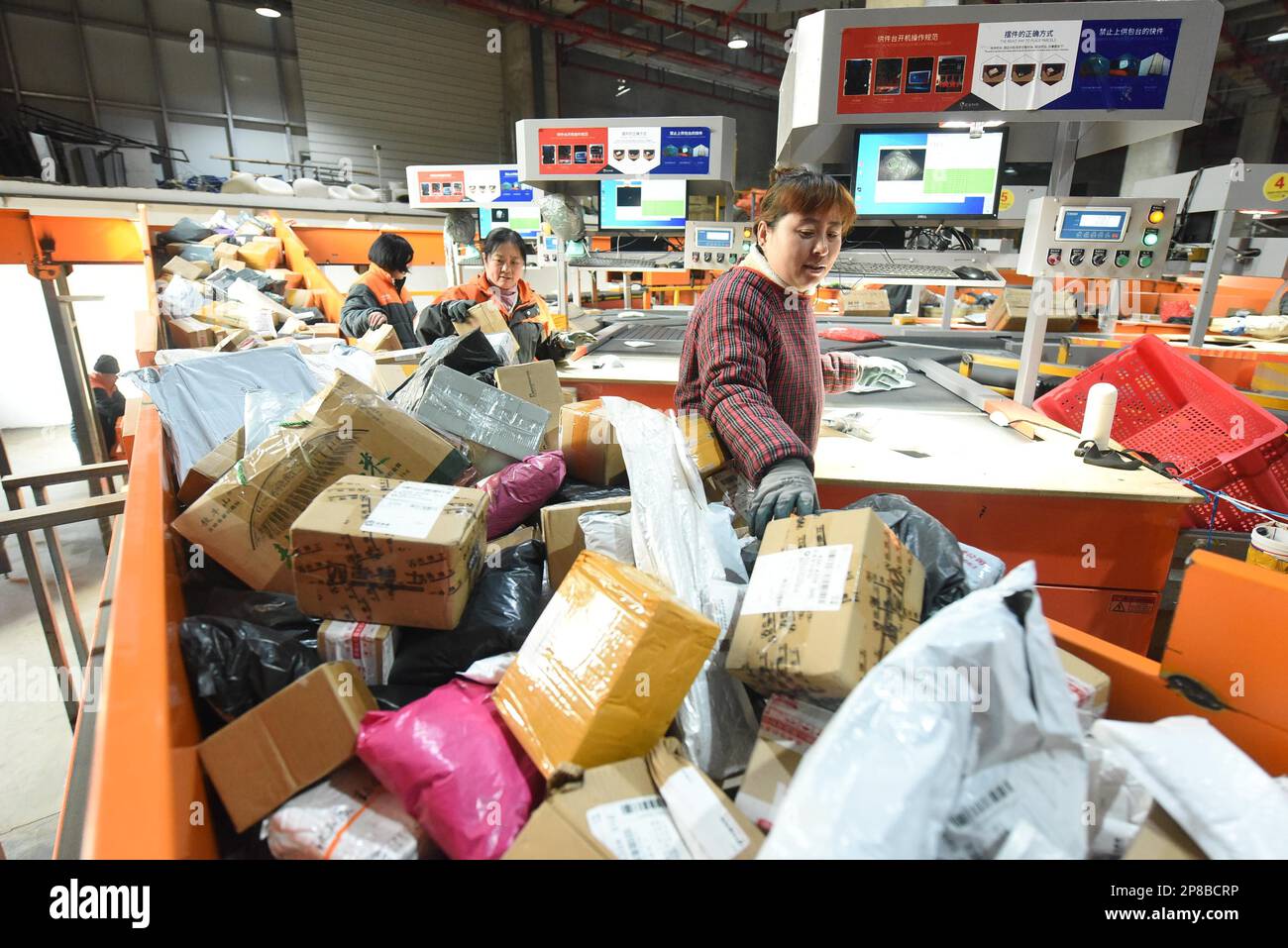 Female workers sort express packages on the assembly line in the e ...